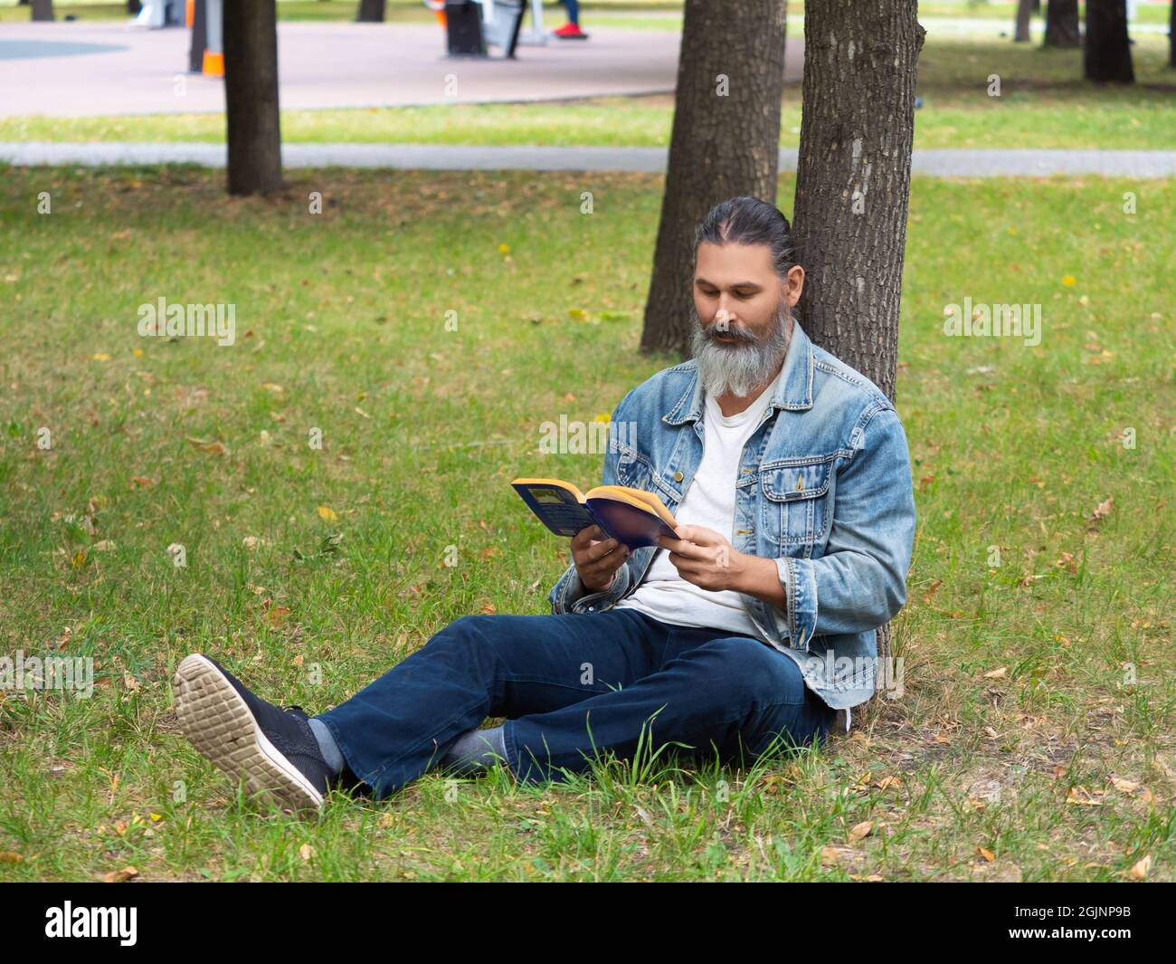 Man sitting under tree reading hi-res stock photography and images - Alamy