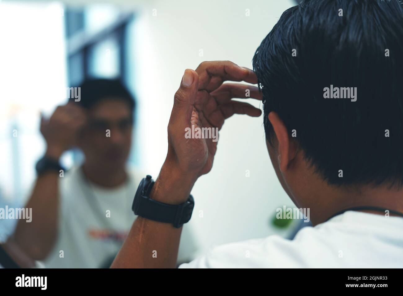 A man is looking in the mirror to preen Stock Photo - Alamy