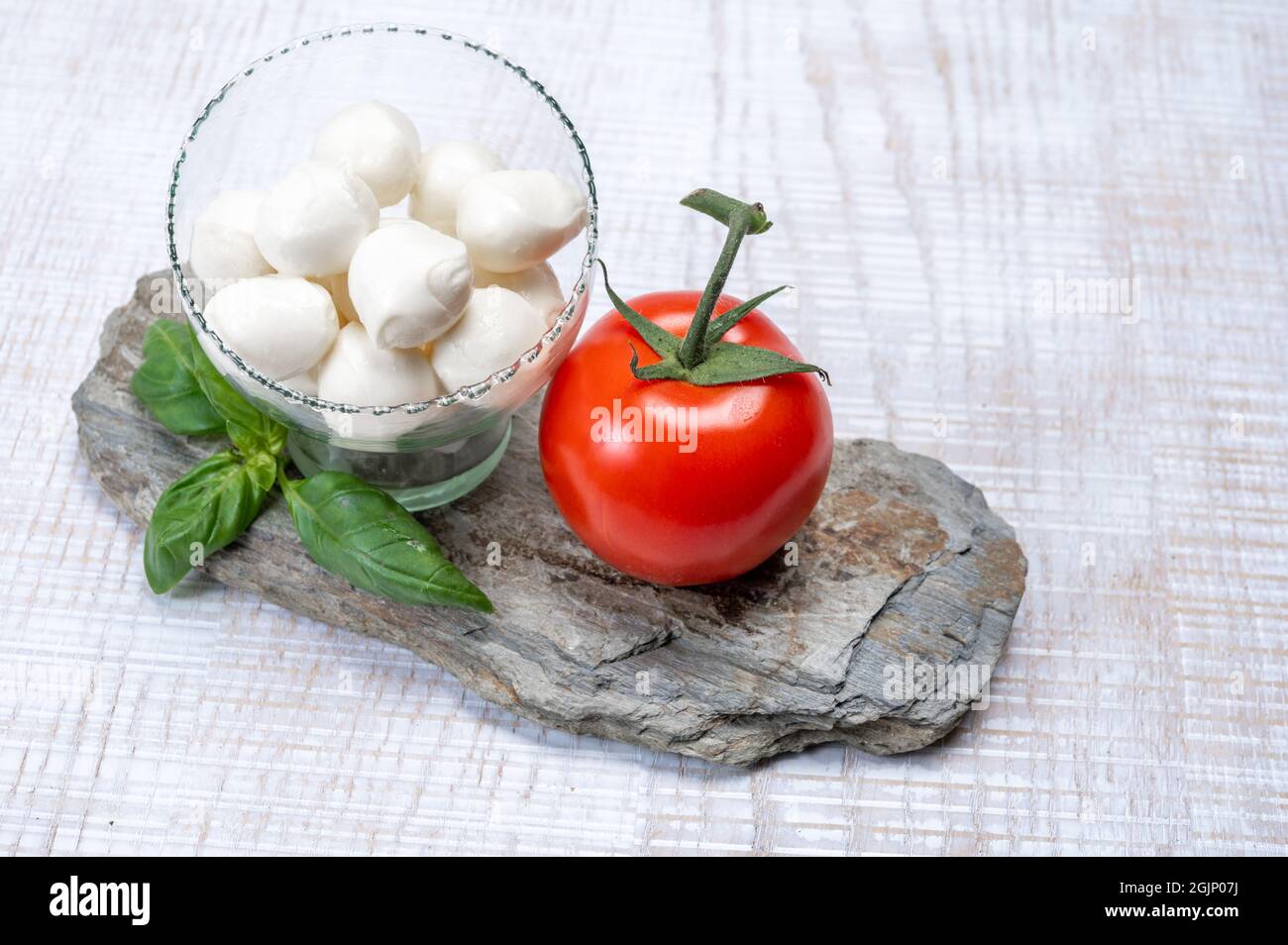 Fresh white soft mini mozzarella balls served with red tomato and fresh ...