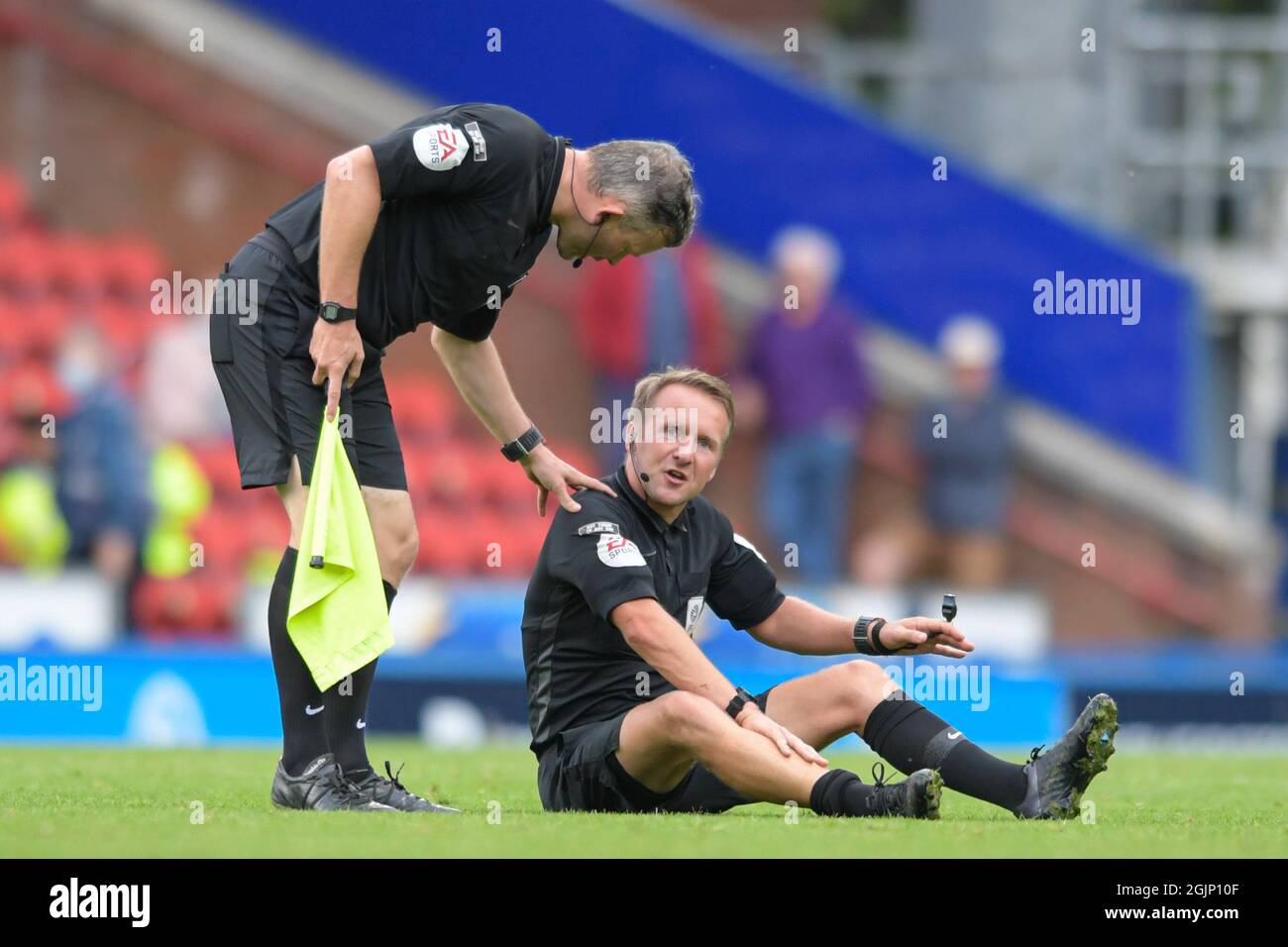 Referee Oliver Langford sits on the pitch after picking up an injury ...