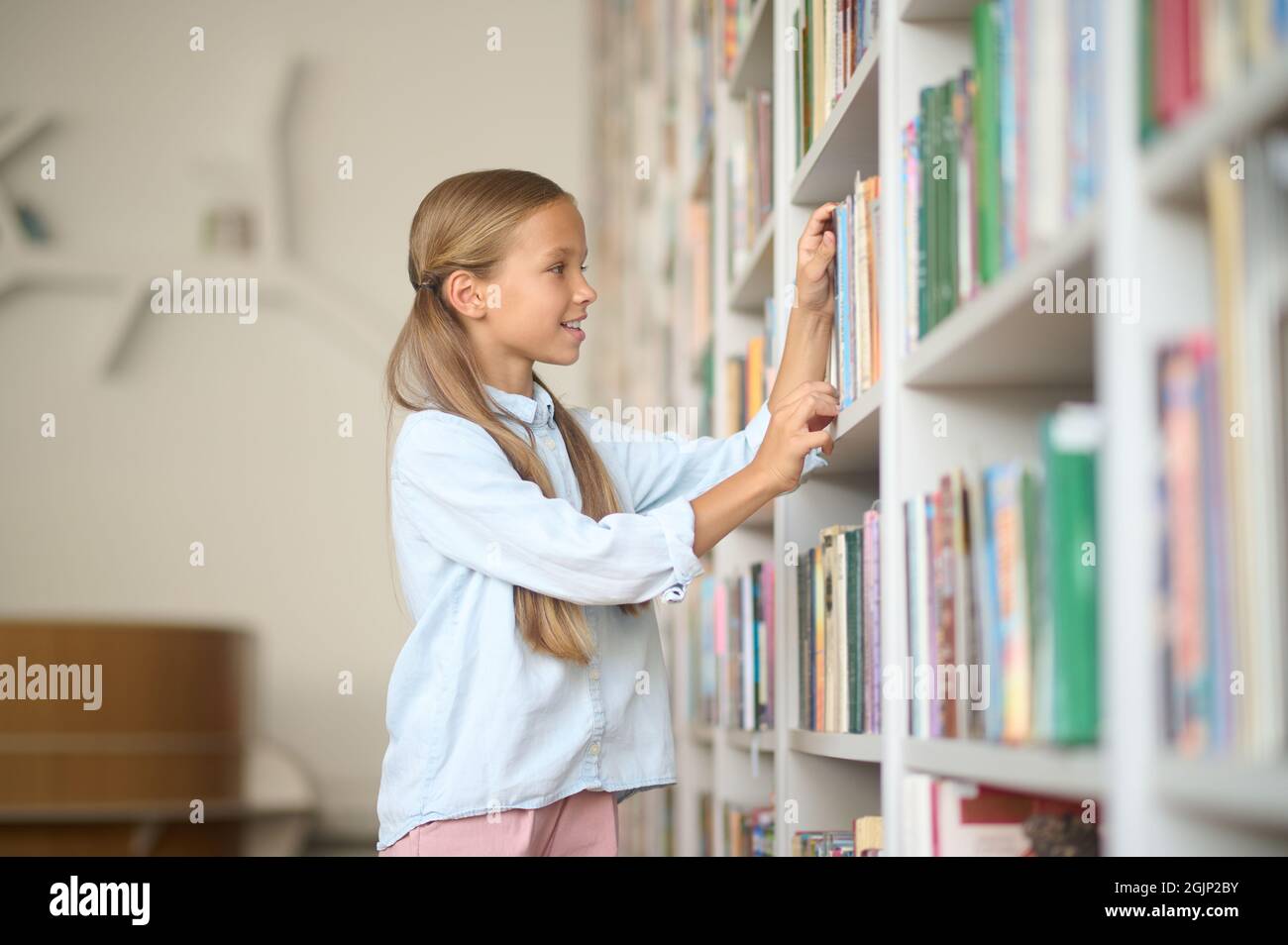 Young girl searching for the right books Stock Photo - Alamy