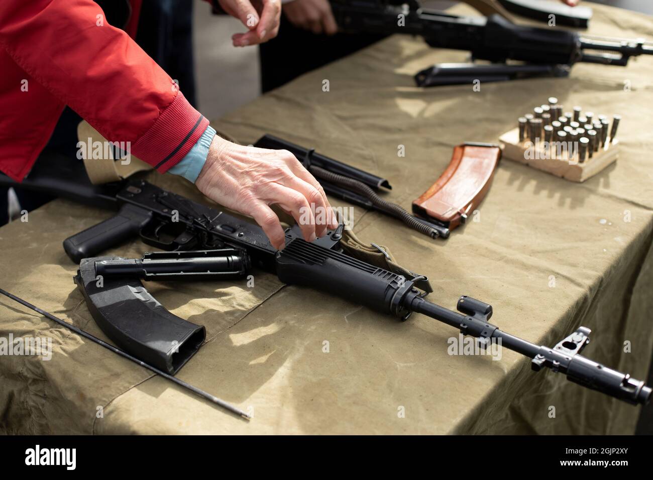 A man disassembles a firearm. A person undergoes military training ...