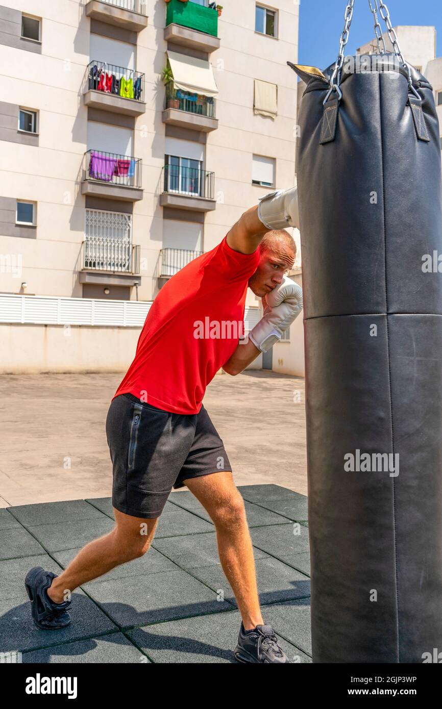 Joyful young man boxing in the street. Sports and health concept ...