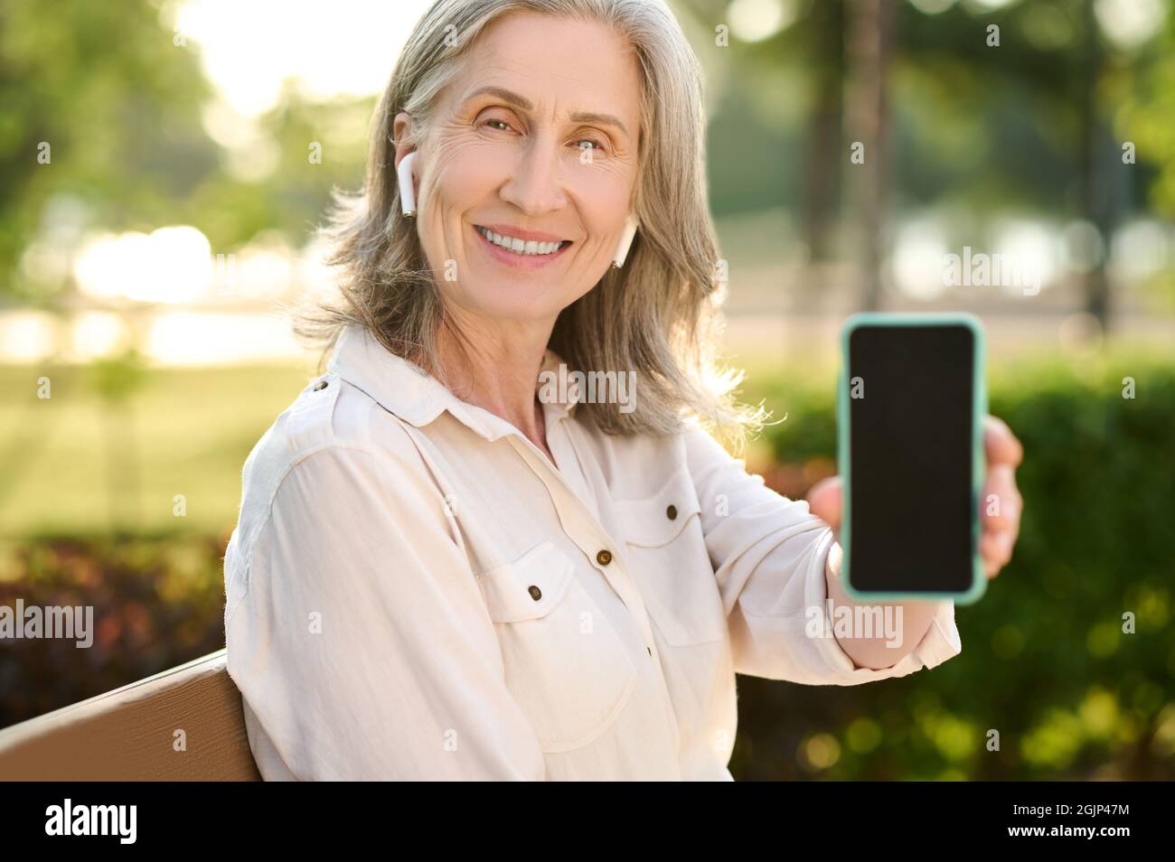 Good looking retirement age woman showing smartphone Stock Photo - Alamy
