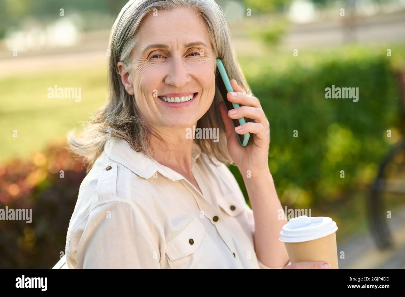 Affable smiling woman communicating by smartphone Stock Photo - Alamy