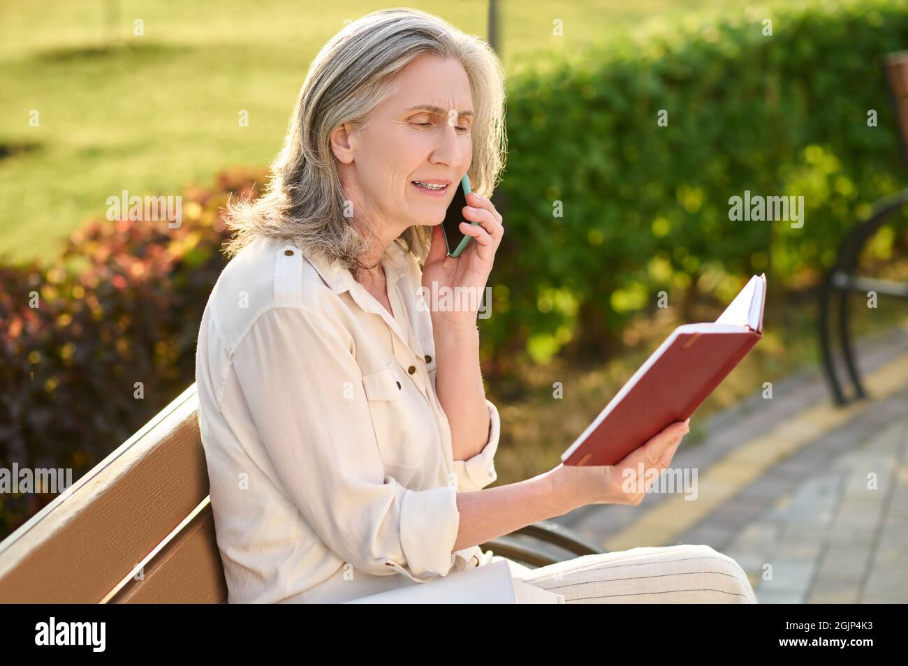 Woman with notebook talking on smartphone Stock Photo - Alamy