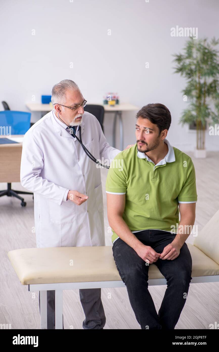 Young man visiting old doctor Stock Photo - Alamy