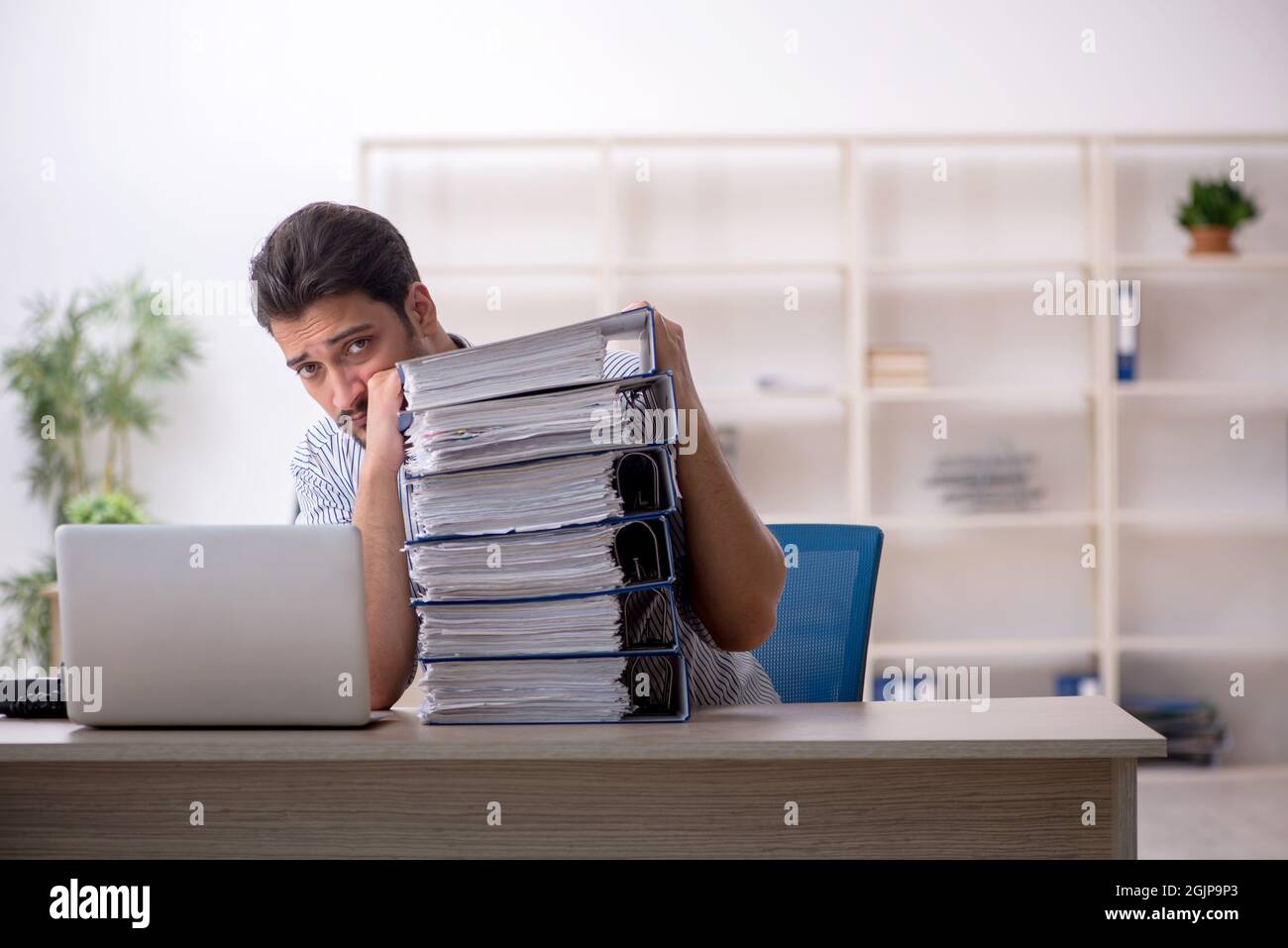 Young businessman employee and too much work at workplace Stock Photo ...