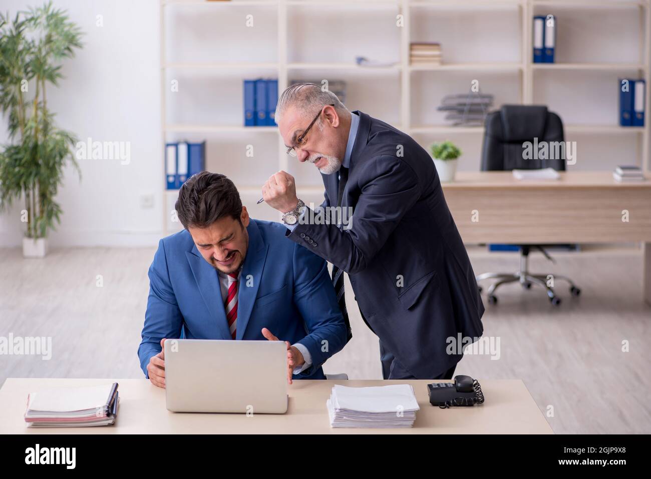 Old boss and young employee in bullying concept Stock Photo - Alamy
