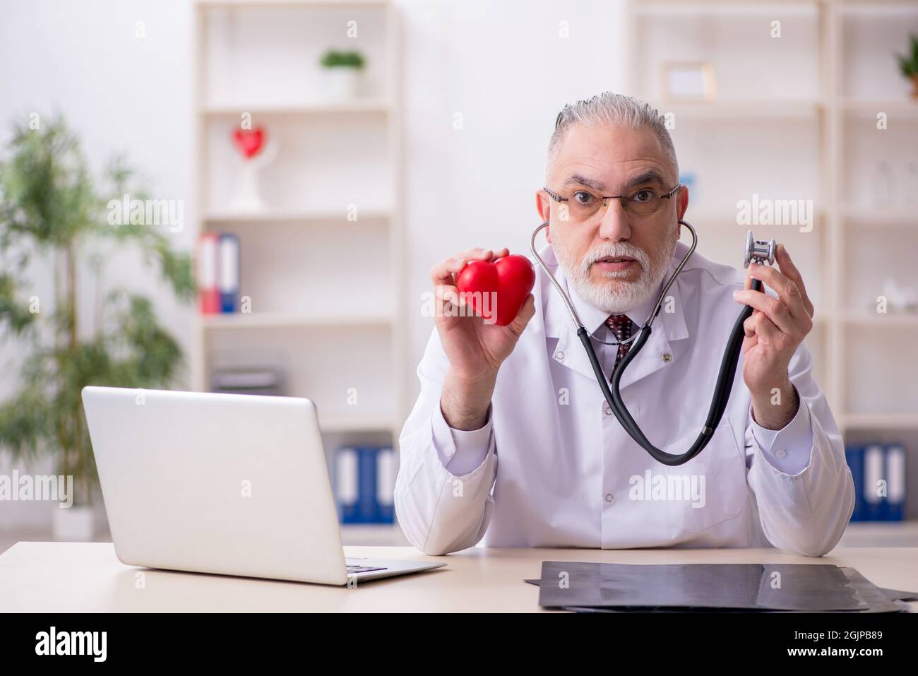Old doctor cardiologist working in the clinic Stock Photo - Alamy