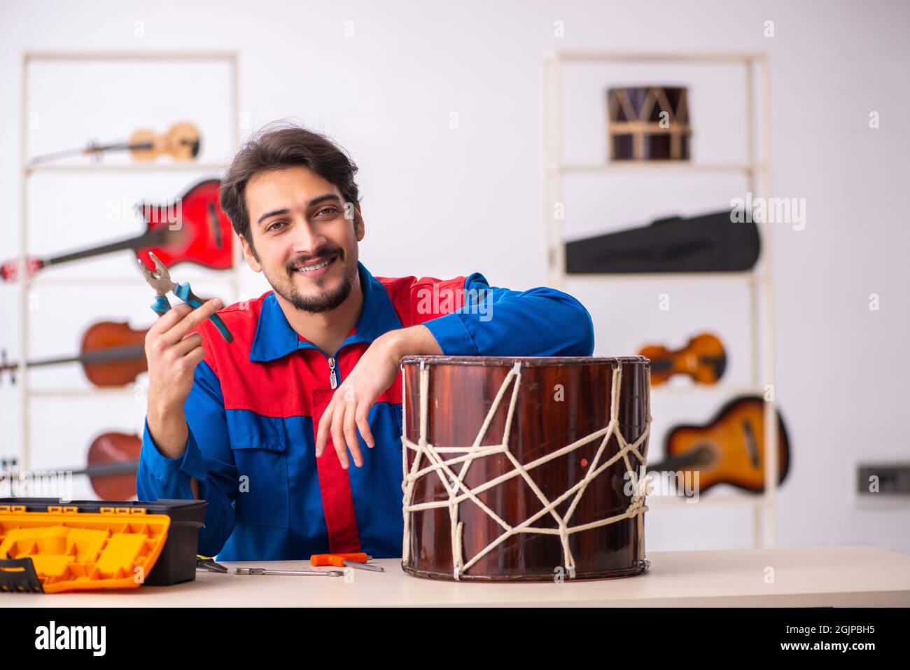 Young repairman repairing musical instruments at workplace Stock Photo ...