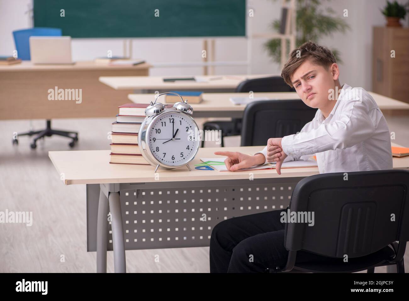 Schoolboy in time management concept in the classroom Stock Photo - Alamy