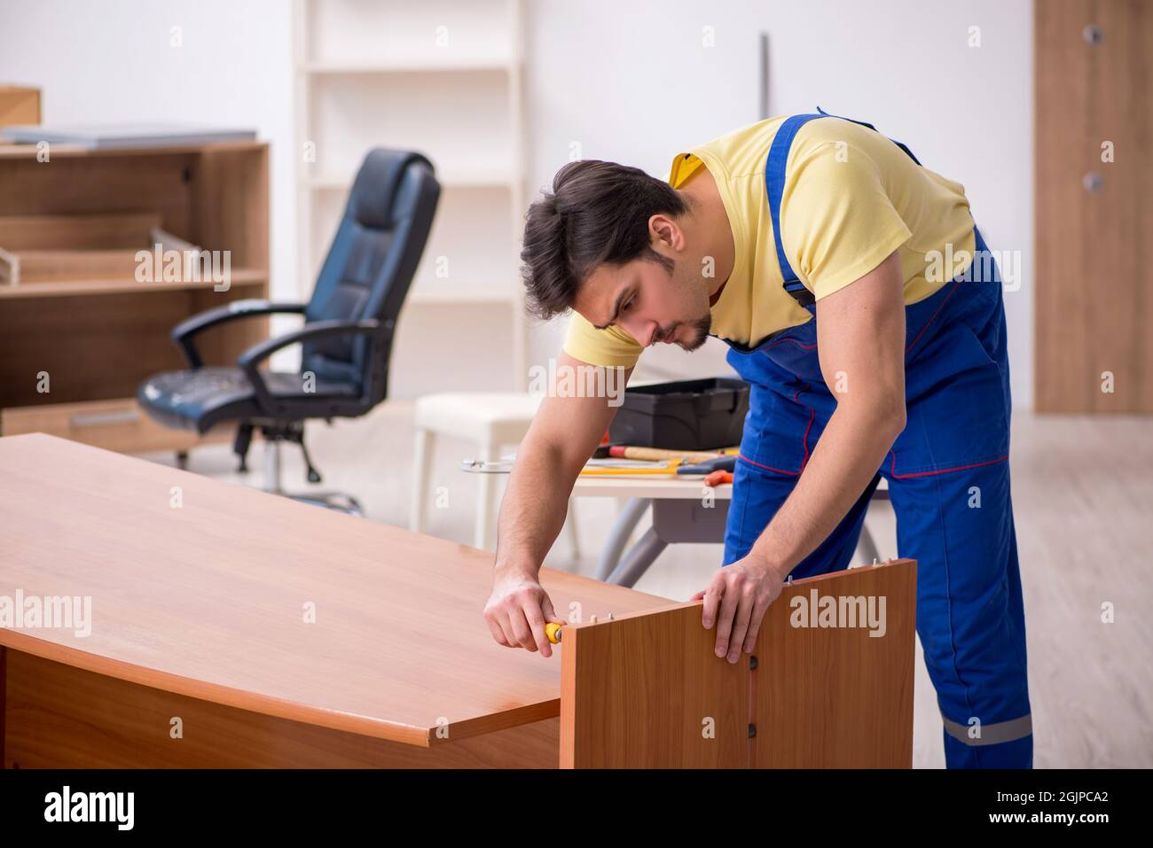 Young carpenter repairing desk in the office Stock Photo - Alamy