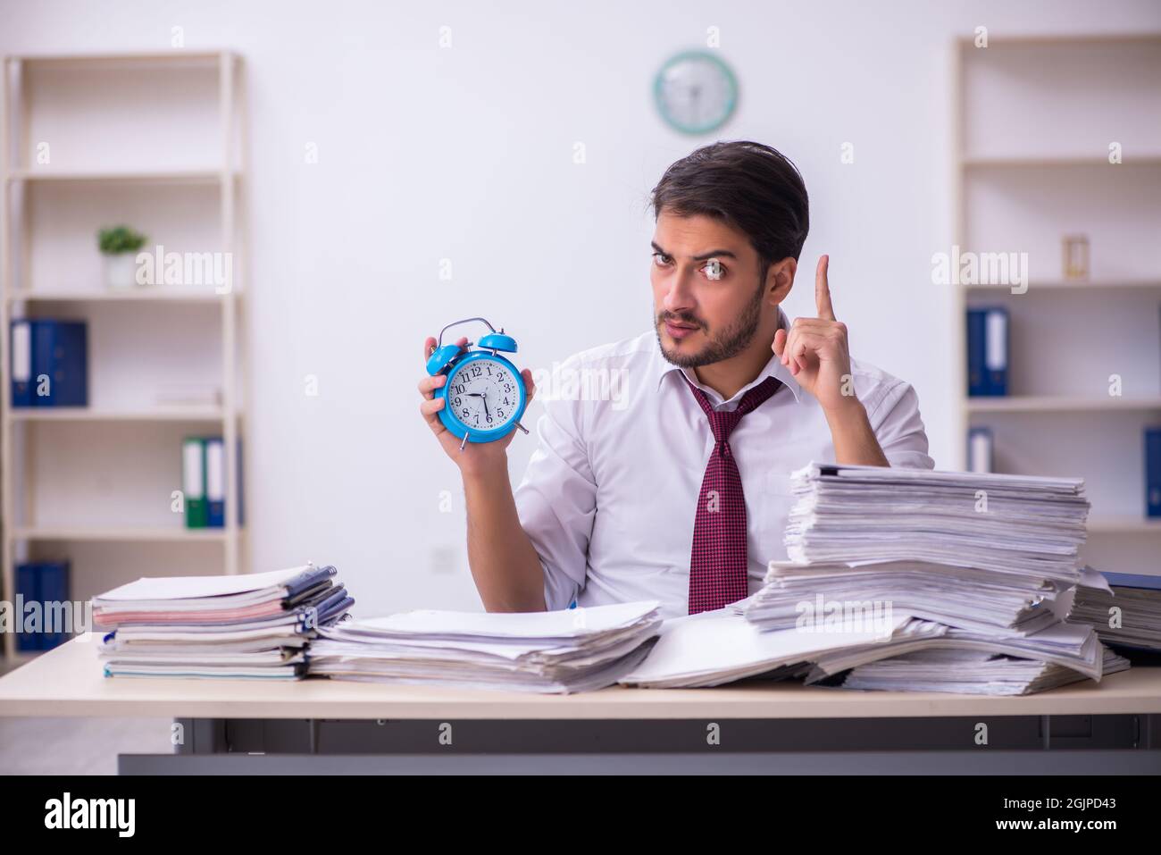Young male employee in time management concept Stock Photo - Alamy
