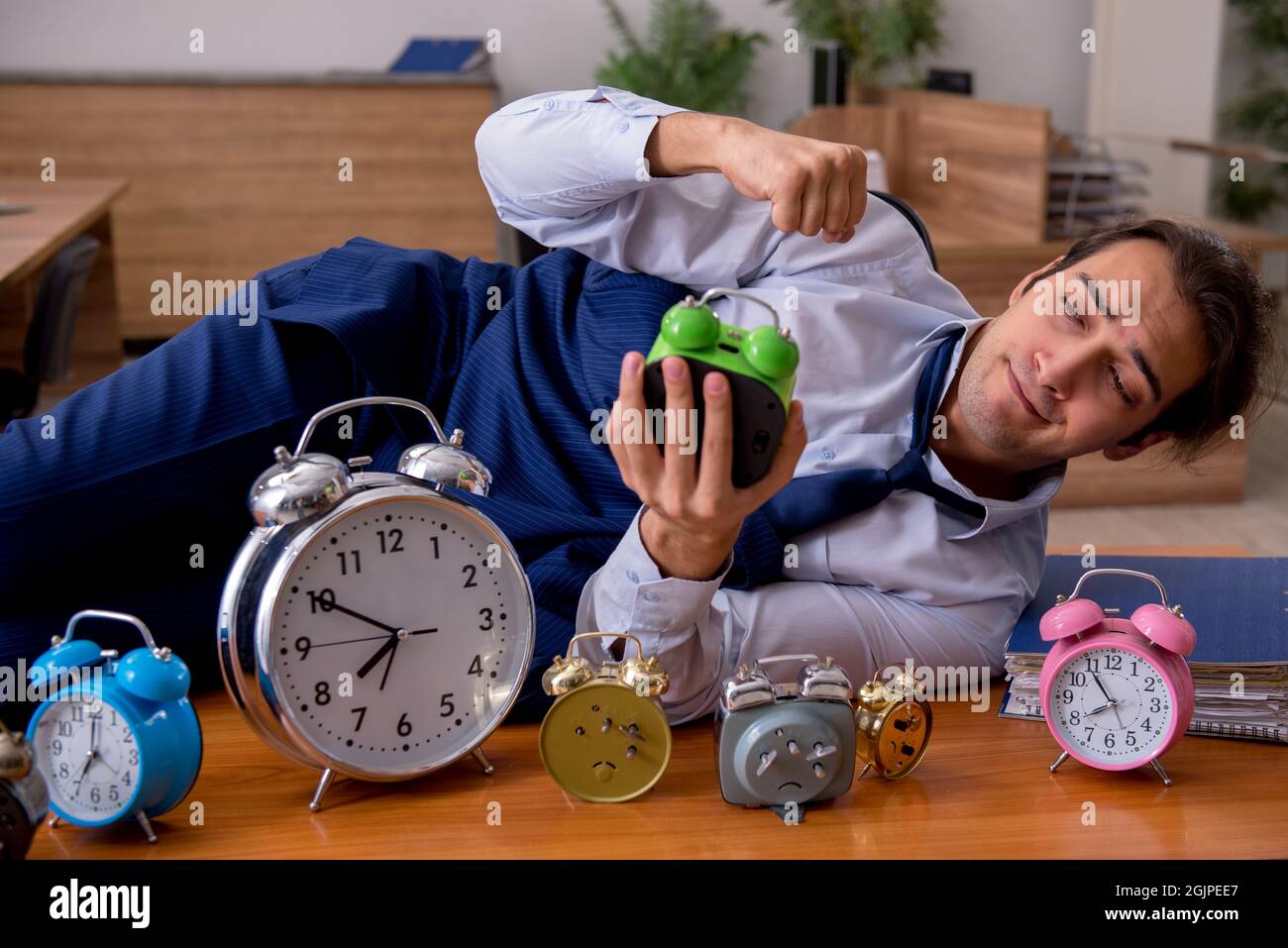 Young businessman sleeping in the office in time management concept ...