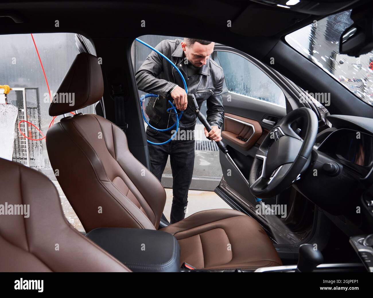 View from inside a car on young man washing car on carwash station ...
