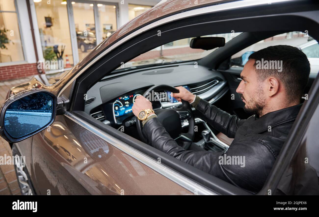 Close-up view of confident, bearded man testing new car in the ...