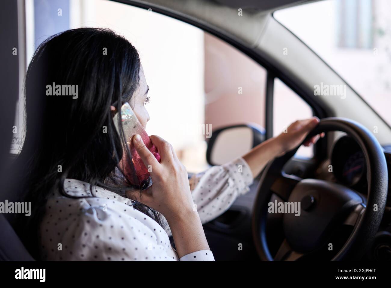 Unsafe driving. Young multiracial woman talking on the phone while ...