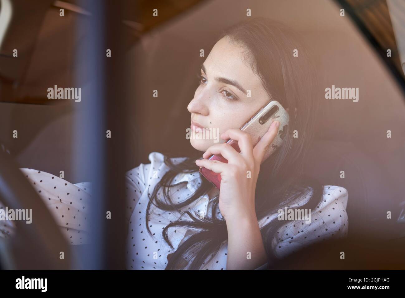 Unsafe driving. Young multiracial woman talking on the phone while ...