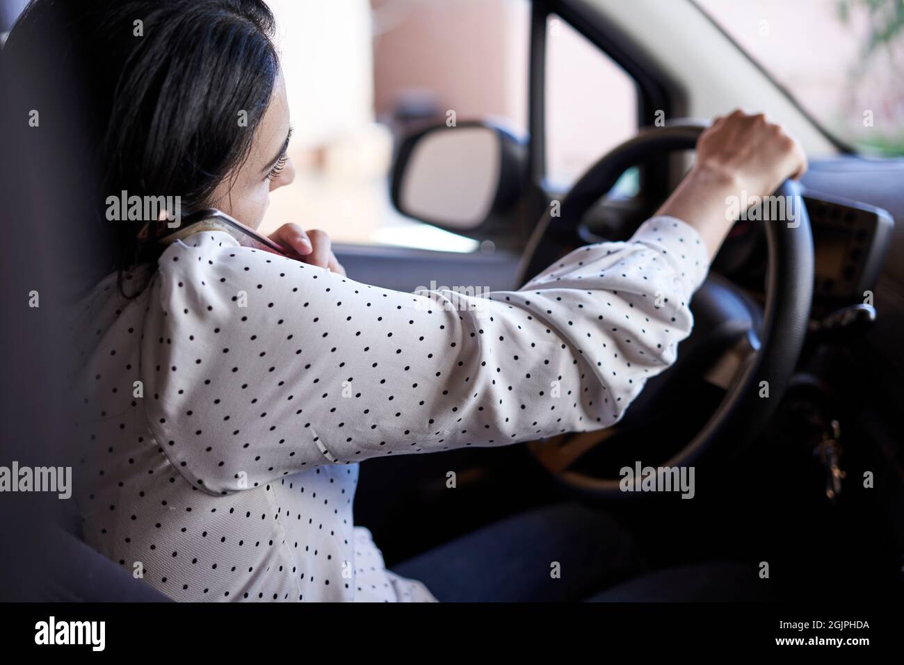 Unsafe driving. Young multiracial woman talking on the phone while ...