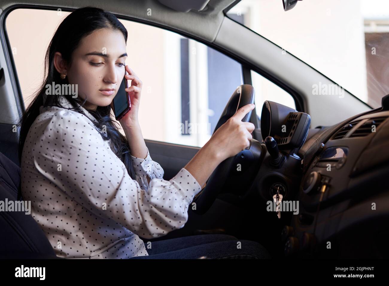 Unsafe driving. Young multiracial woman talking on the phone while ...