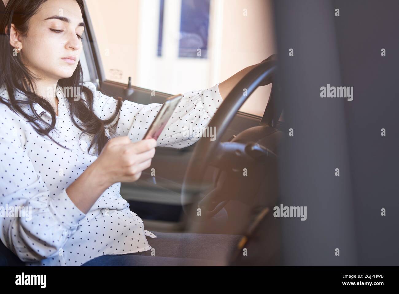 Young multiracial woman texting and driving car. Woman using cellphone ...