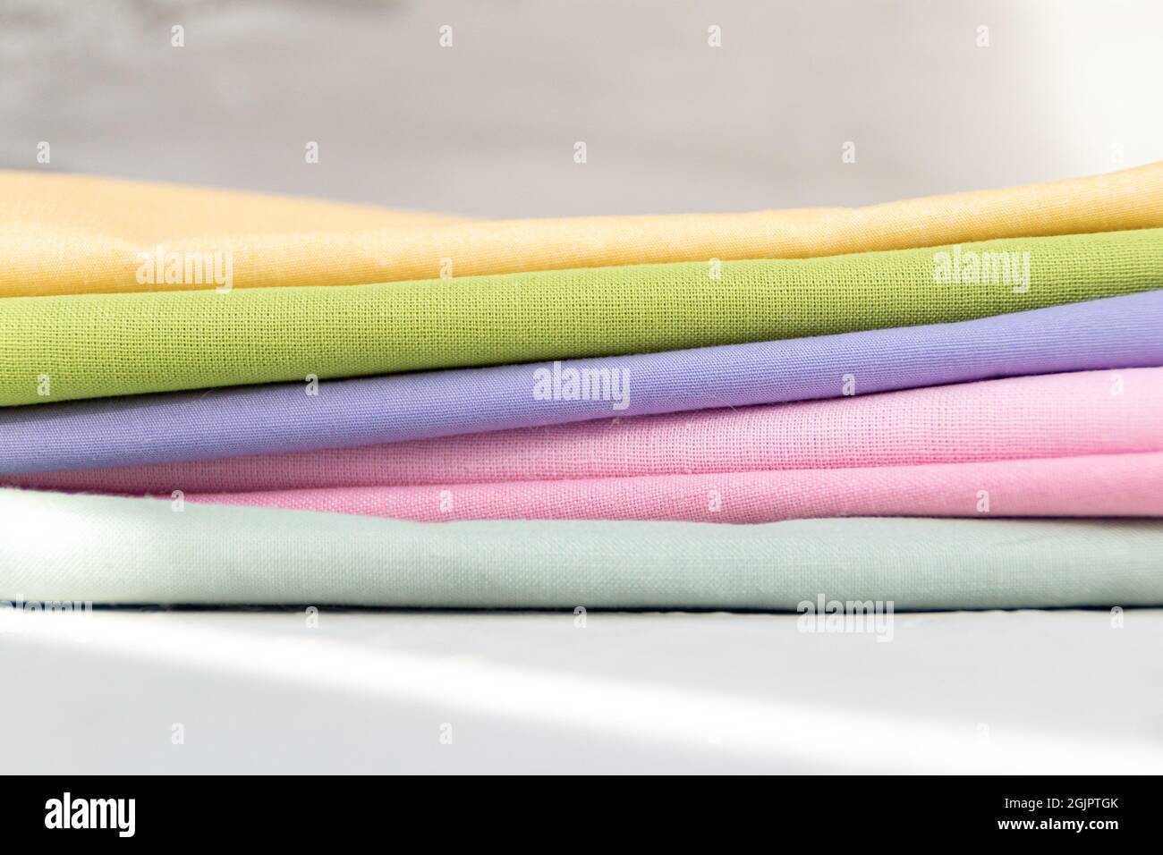 Stack of colorful cotton fabric against grey background, slow fashion ...