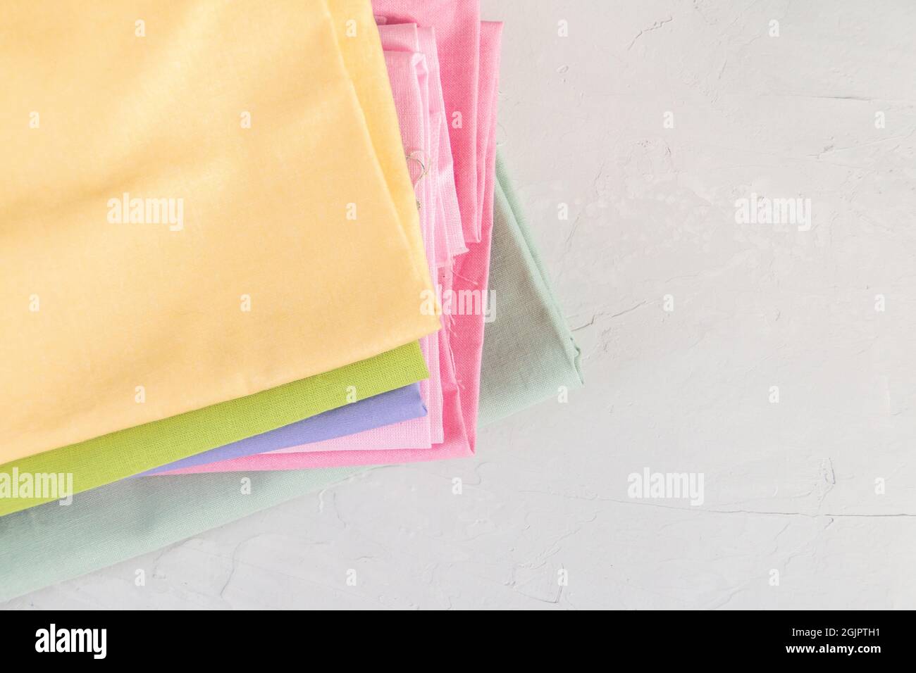 Stack of colorful cotton fabric against grey background, slow fashion ...