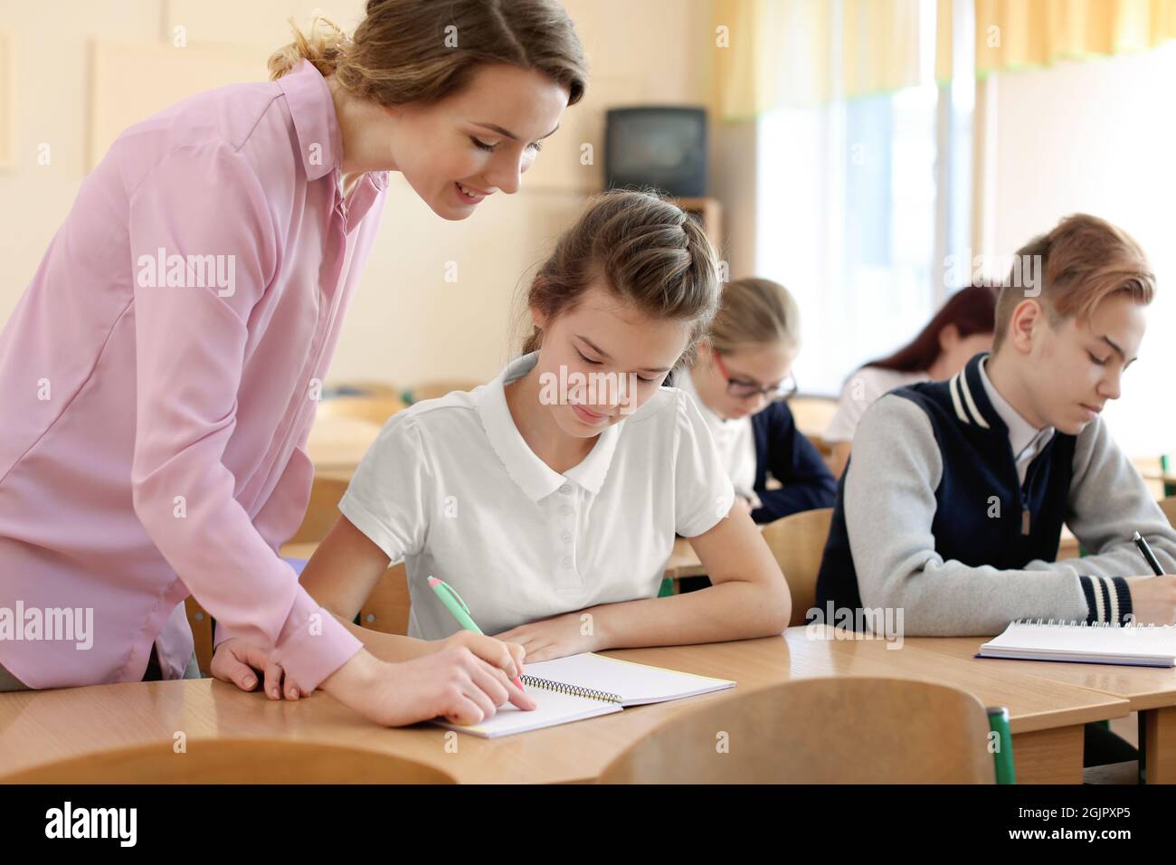 Teacher explaining exercise to pupil in classroom Stock Photo - Alamy