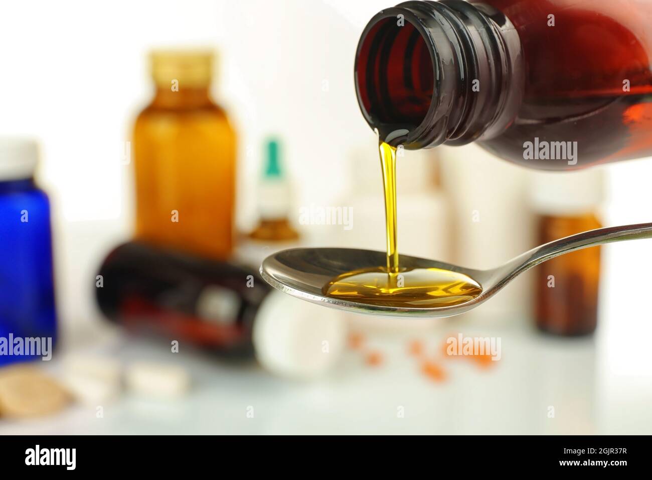 Pouring cough syrup into spoon on blurred background of medicines Stock ...
