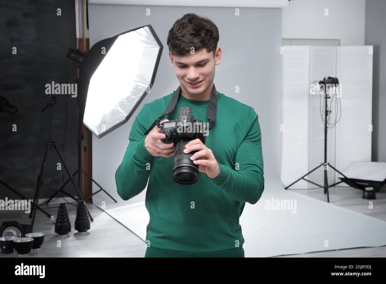Young professional photographer with camera in studio Stock Photo - Alamy