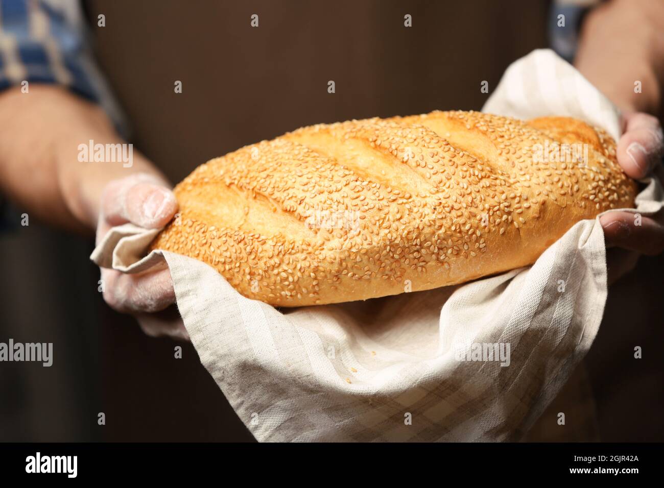 Male hands holding wheaten baton with sesame, closeup Stock Photo - Alamy