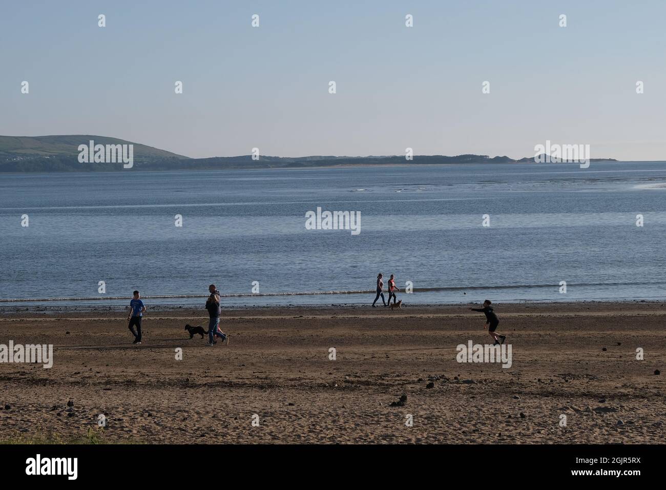 Beachgoers at Llanelli beach looking south toward the Gower peninsula ...