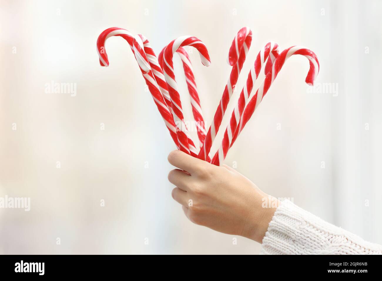 Female hand holding bunch of candy canes, closeup Stock Photo - Alamy