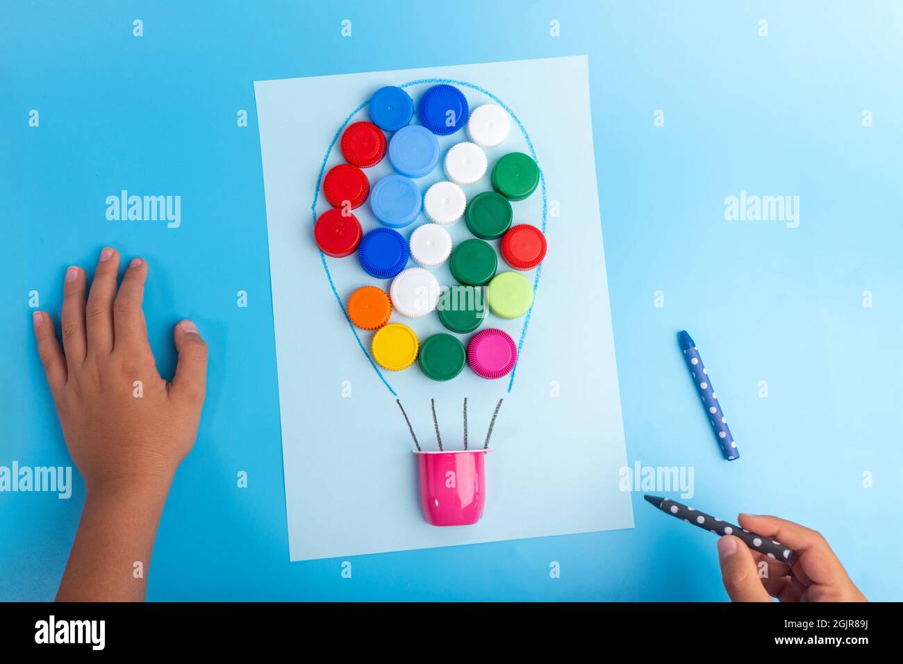 child make a craft from recycled plastic bottle caps Stock Photo - Alamy