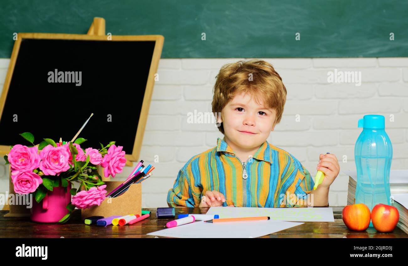 School boy in classroom. Little child writing with colorful pencils ...