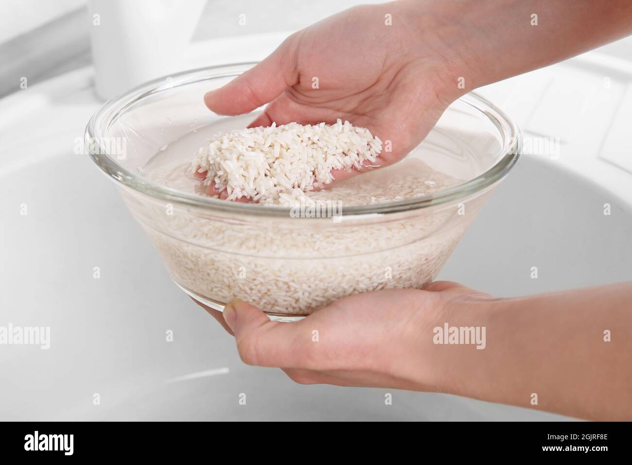 Woman rinsing rice in glass bowl with water Stock Photo - Alamy