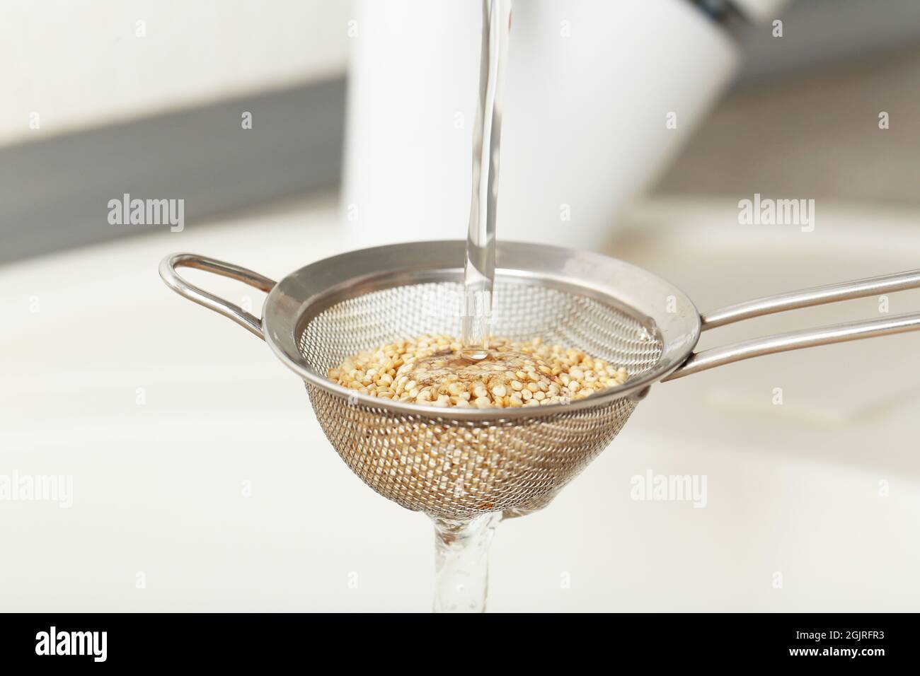 Washing quinoa seeds in sieve over sink Stock Photo - Alamy