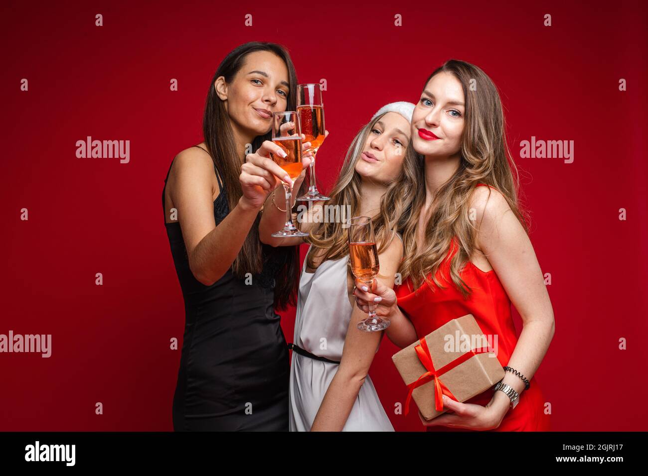Happy beautiful female friends posing together while making a toast ...
