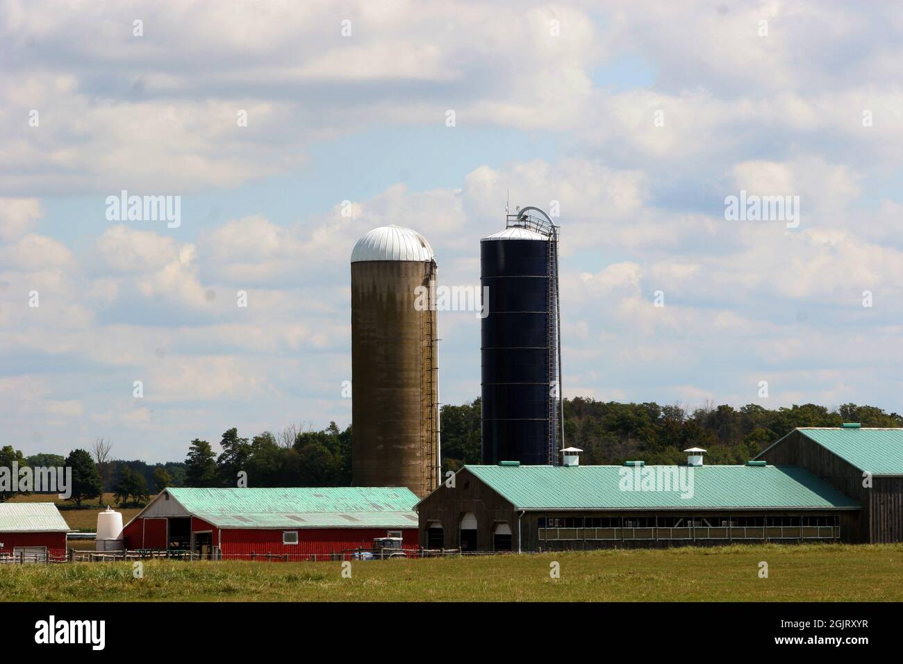 Farm buildings with silos behind farm field Stock Photo - Alamy