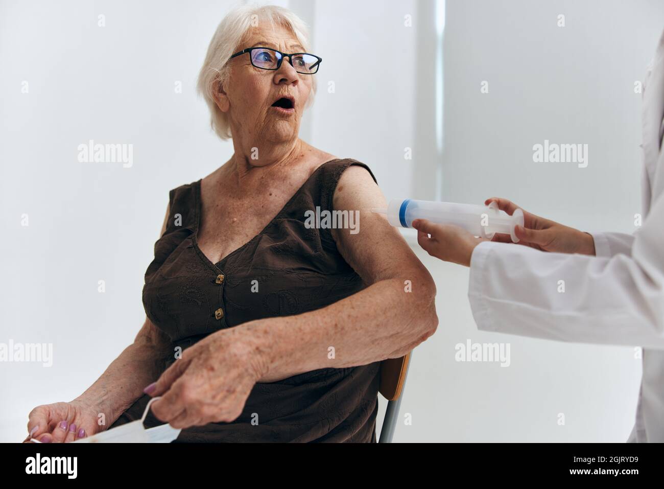 Nurse giving injection to an elderly woman with a syringe hospital Stock Photo - Alamy