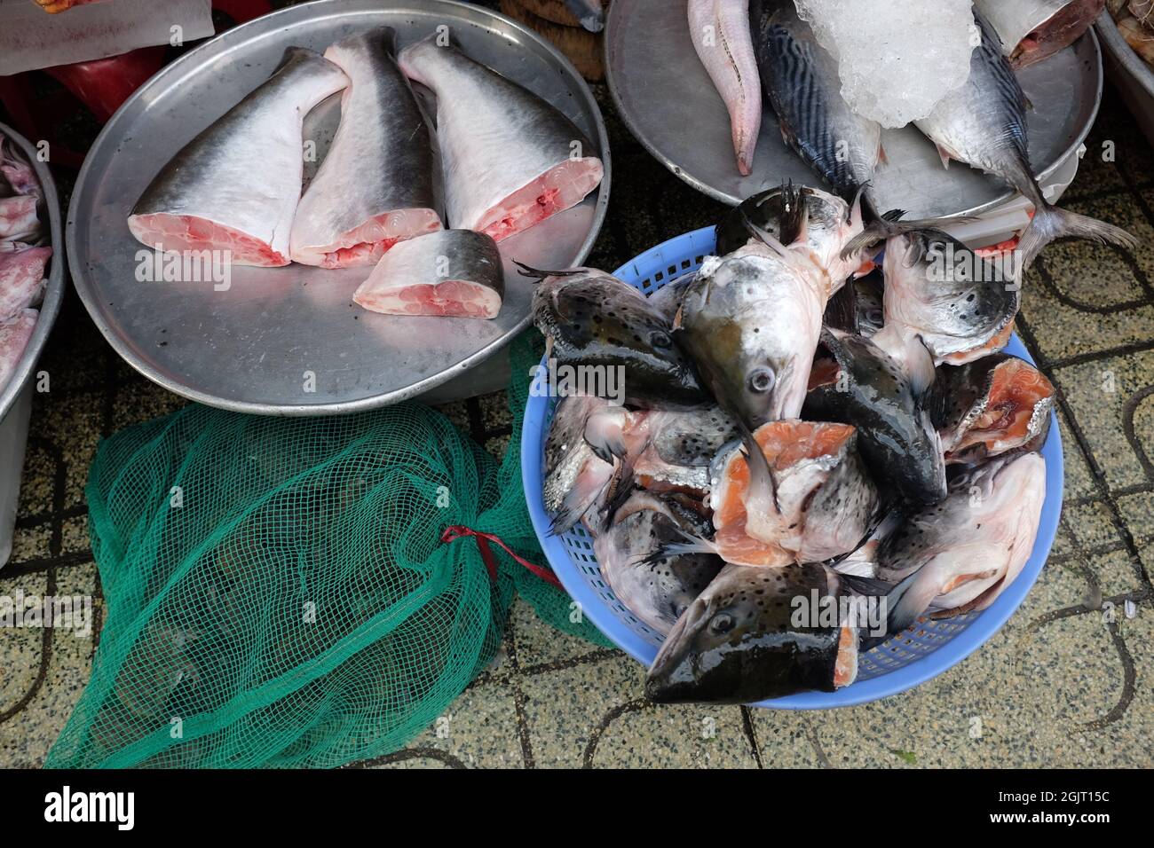 A pile of cut off fish heads in a basket with their headless bodies in ...