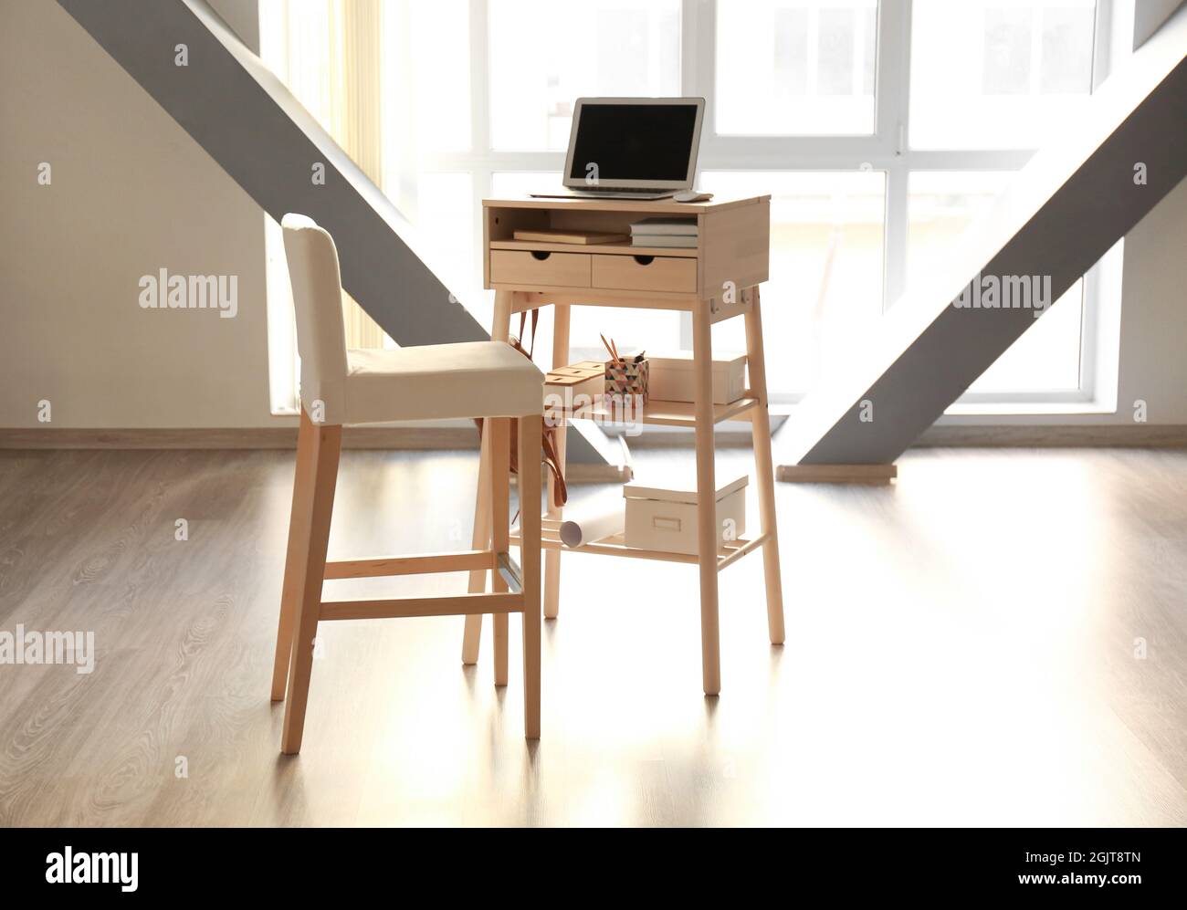 High desk with laptop and chair in room Stock Photo - Alamy