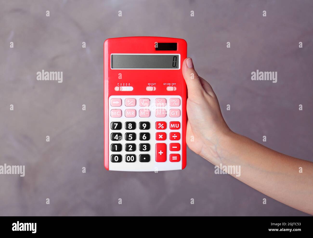 Hand holding red calculator on color background Stock Photo - Alamy