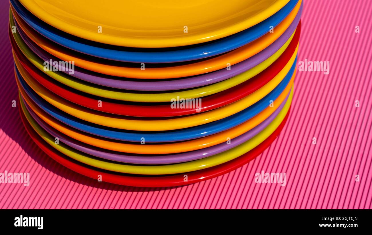 Different colored plates stacked on pink background. Dishes in red ...