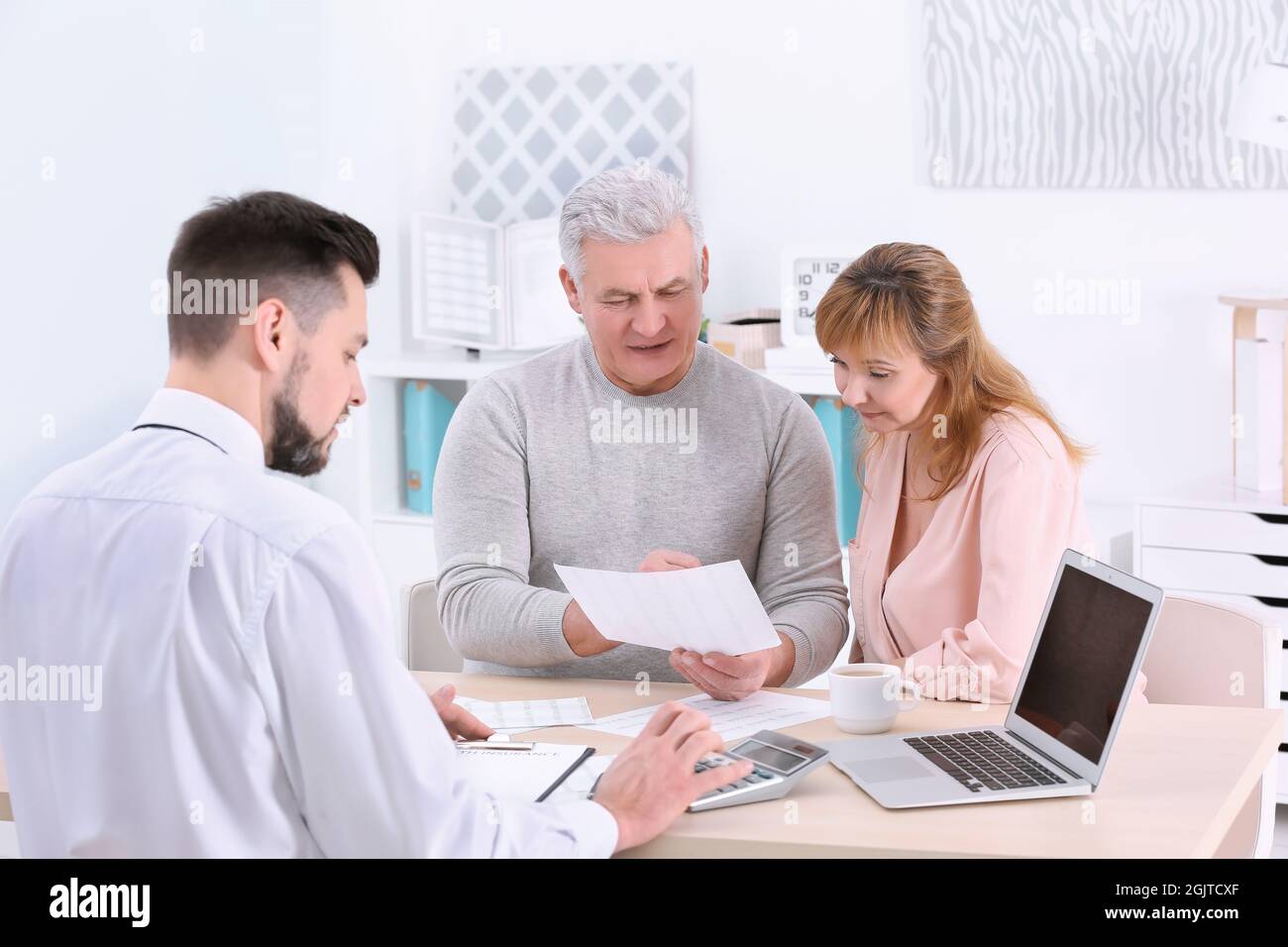 Middle aged couple signing contract at insurance agency office Stock ... Middle aged couple signing contract at insurance agency office Stock ...