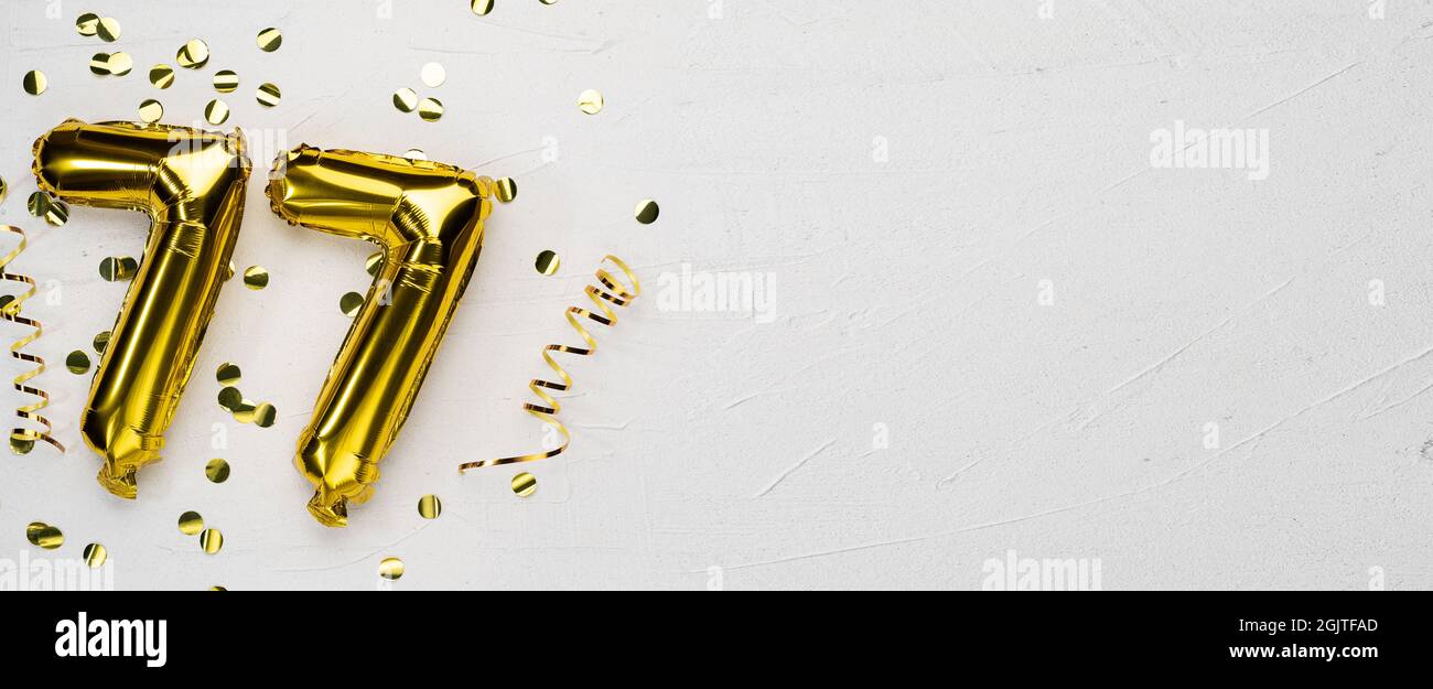 golden foil balloon number seventy seven. Birthday or anniversary card with the inscription 77 ...