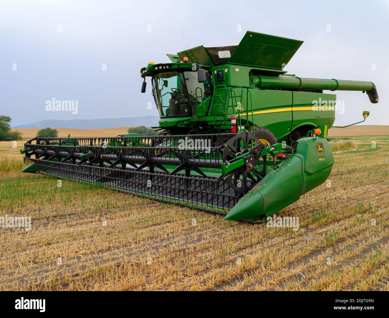 A John Deere S680 combine is parked in a wheat field in Idaho, USA ...
