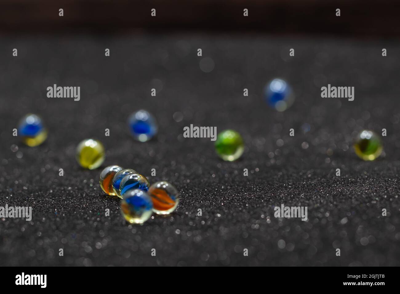 coloured glass marbles scattered on black background Stock Photo - Alamy