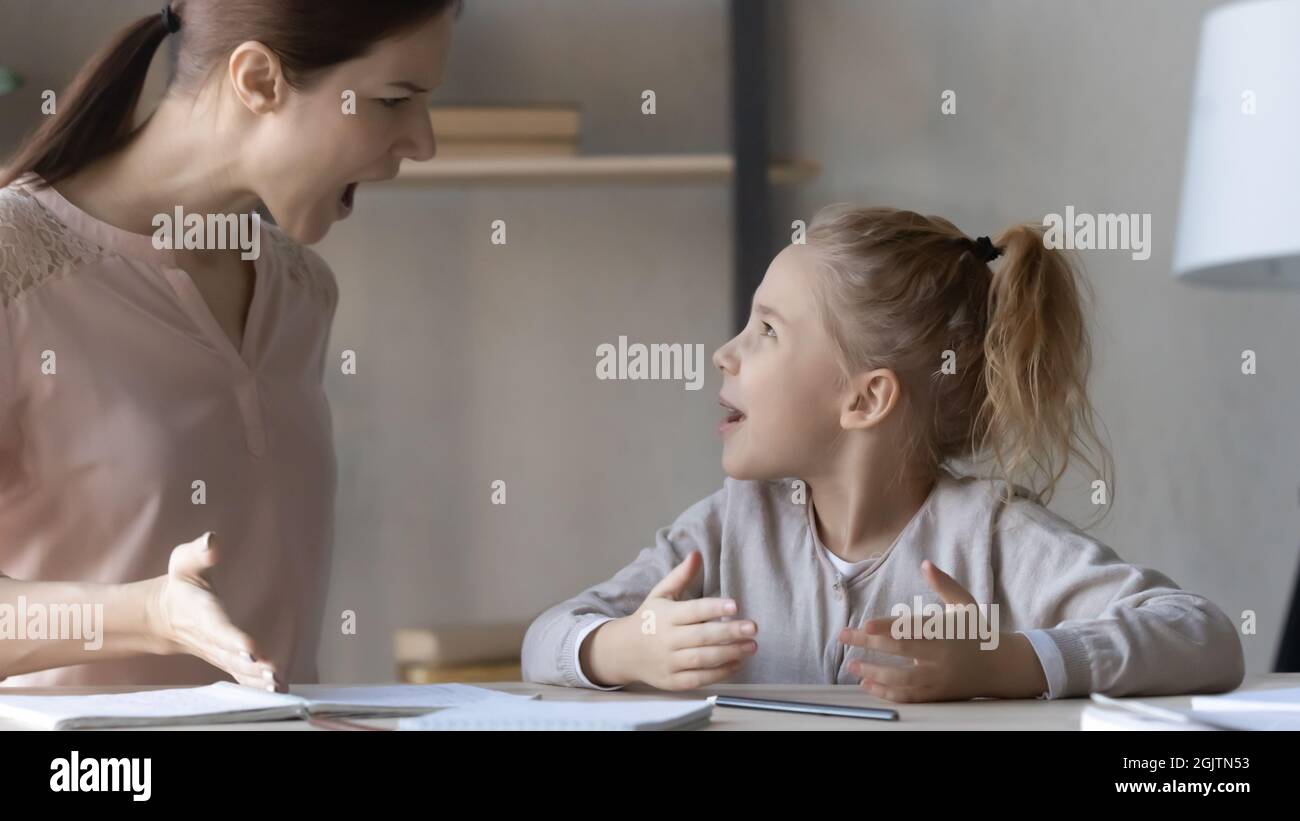 Angry strict young mother arguing with stressed small kid daughter ...